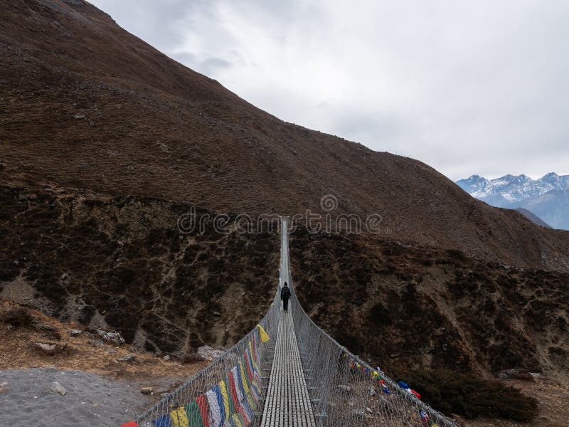 Shot of a Person Walking on a Swinging Bridge in between Mountains ...
