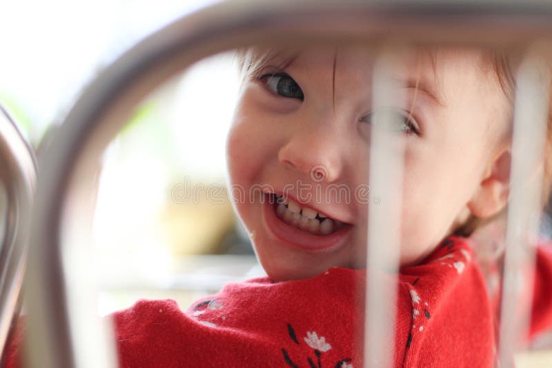 A Shot of a Smiling Little White Child in the Kitchen through the Bars ...