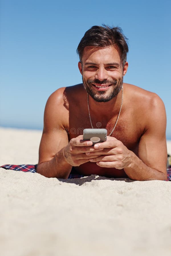Wish You Were Here. Shot of a Young Man Using a Cellphone at the Beach ...