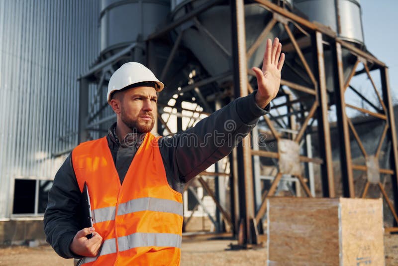 Showing Stop Gesture. Construction Worker in Uniform is Outdoors Near ... Showing Stop Gesture. Construction Worker in Uniform is Outdoors Near ...