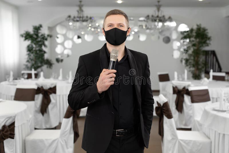 Showman in a Suit and Protective Mask with a Microphone in His Hands ...