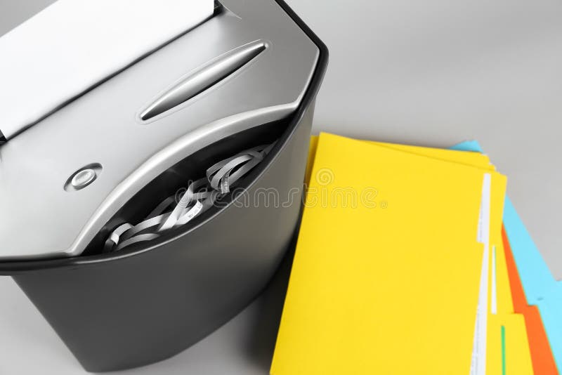 Shredder with Sheet of Paper and Colorful Folders on Grey Background ...