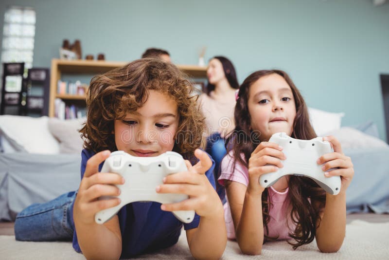 Siblings with Controllers Playing Video Game on Carpet at Home Stock ...