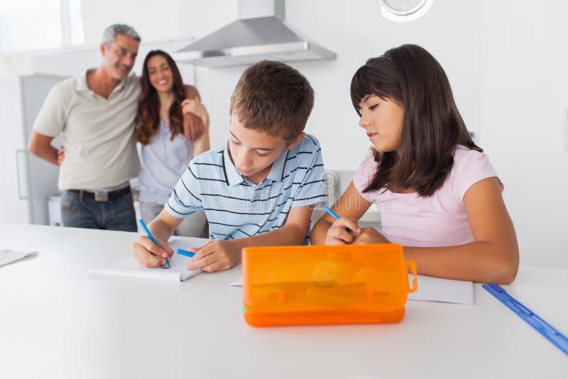 Siblings Drawing Together in Kitchen with Their Parents Smiling Stock ...