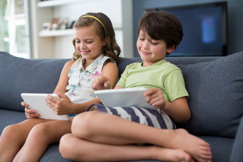 Siblings Using Digital Tablet in Living Room Stock Image - Image of ...
