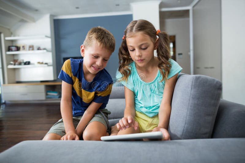 Siblings Using Digital Tablet in Living Room Stock Photo - Image of ...