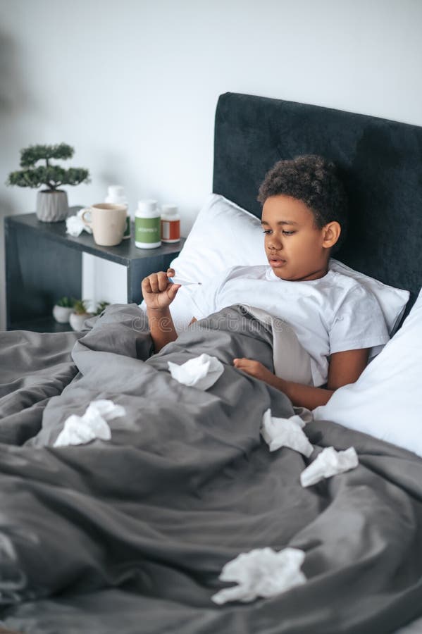 Sick Boy Lying in Bed with Fever and Checking Temperature Stock Photo ...