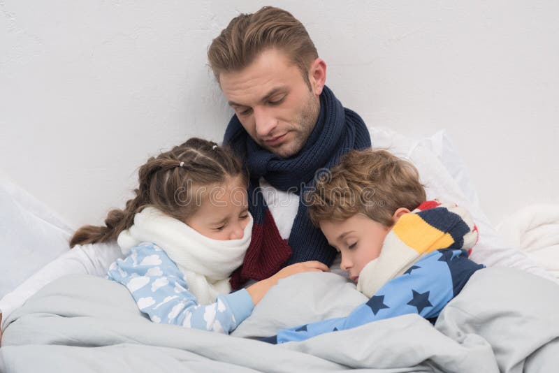 Sick Father with Son and Daughter Lying in a Bed with Scarfs Over Stock ...