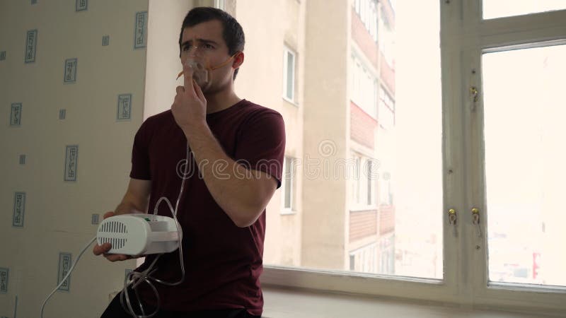 Sick Man Breathing with Inhaler while Standing by the Window Stock ...