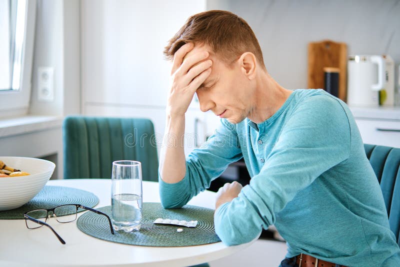 Sick Man in the Kitchen in Front of Pills and a Glass of Water Stock ...