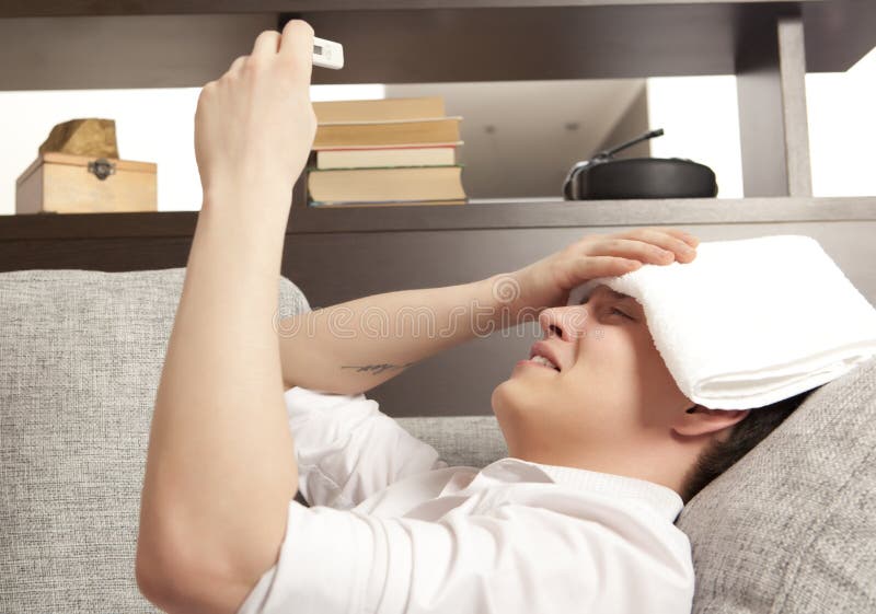 Sick Young Man Lying on Sofa Checking His Temperature Stock Photo ...