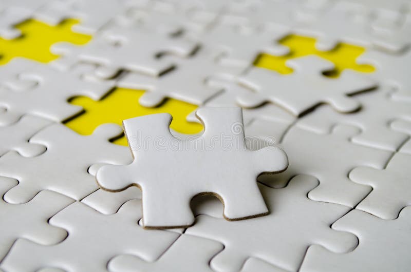 Side Close Up of White Jigsaw Puzzle Pieces Placed on a Bright Yellow ...