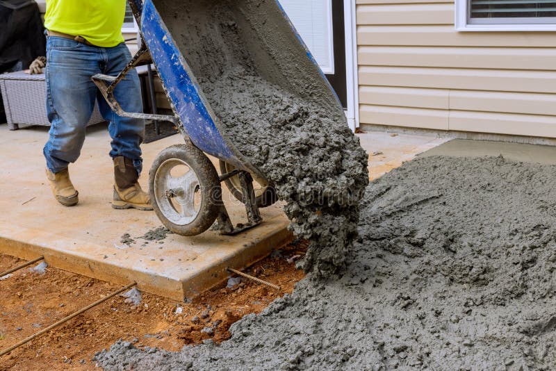 On the Side of the House, a Construction Worker Pours Cement from a ...