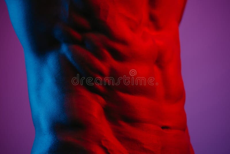A Side Photo of the Abs of a Bodybuilder Under Blue and Red Lights ...