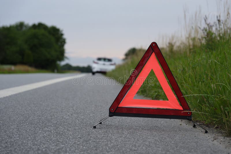 At the Side of the Road is a Warning Triangle, Behind it a White Car ...