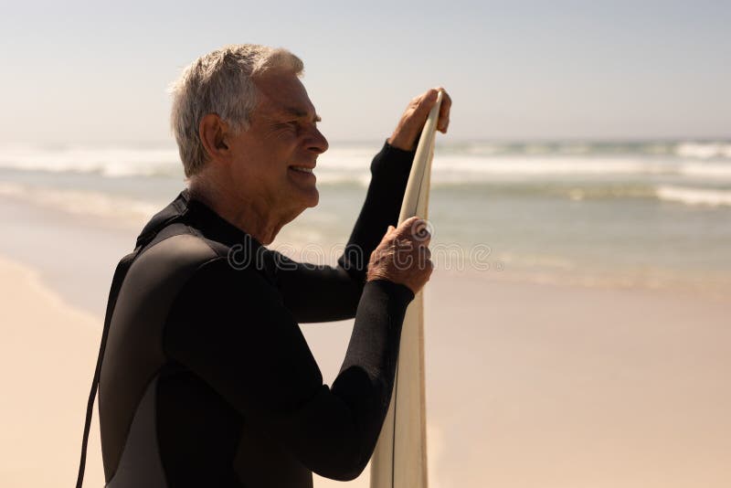 Side View of Senior Male Surfer Standing with Surfboard on the Beach ...
