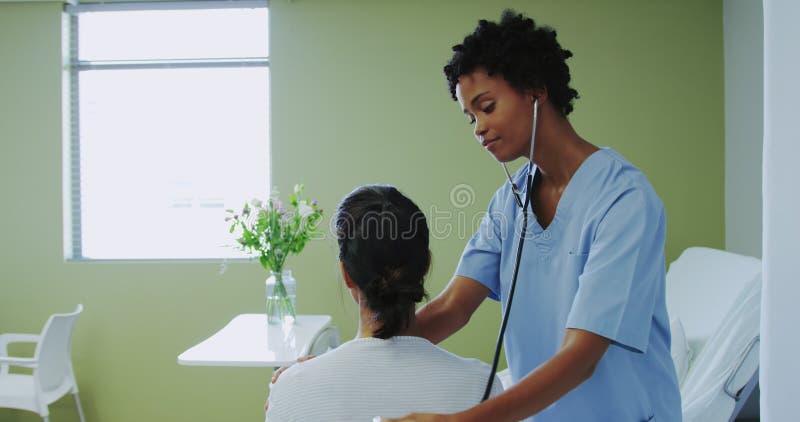 Side View Of African American Female Doctor Examining Female Patient In