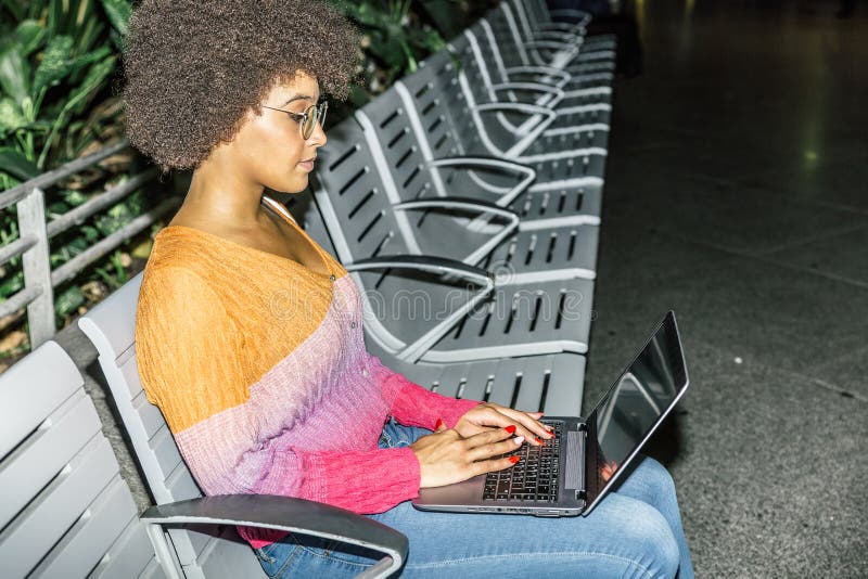 Side View of an African American Woman Working on Her Laptop Sitting at ... Side View of an African American Woman Working on Her Laptop Sitting at ...