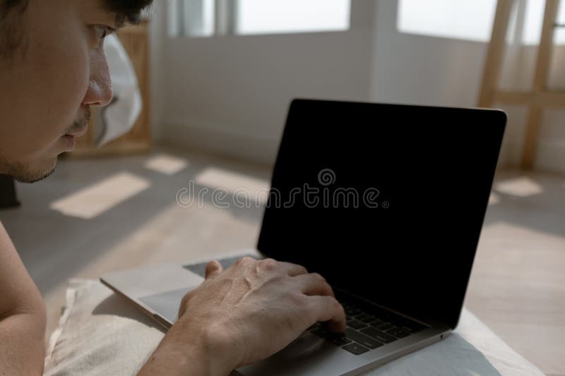 Side View of Asian Man Using Computer, Lying on Floor while Working on ...