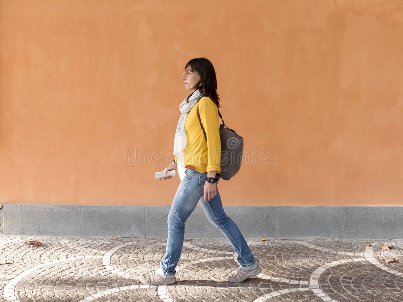 Side View of a Backpacker Traveler Walking Against Orange Wall in the ...