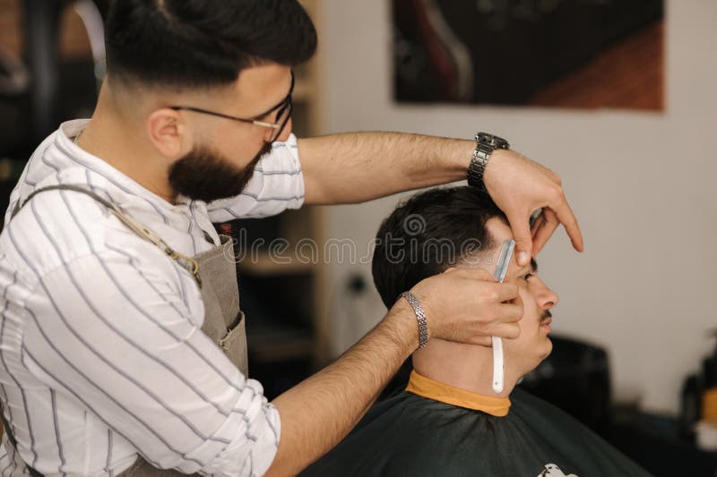 Side View of Barber Using Sharp Blade for Shaving. Handsome Customer ...
