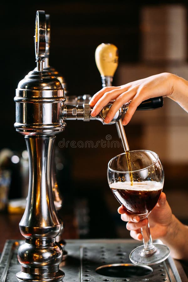 A Man Pouring Draft Lager Beer into a Dimpled Glass Mug in a Modern Pub ...