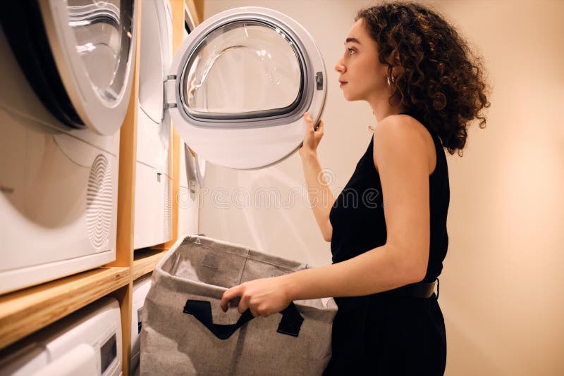 Side View of Beautiful Girl Loading Clothes into Washing Machine in ...