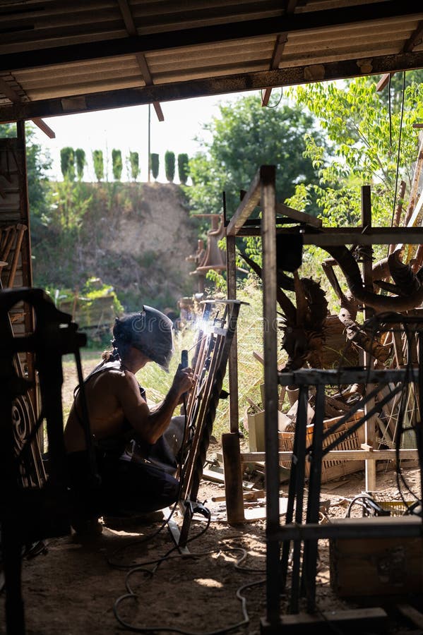 Side View of Blacksmith Welding a Piece of Iron in His Home Workshop ...