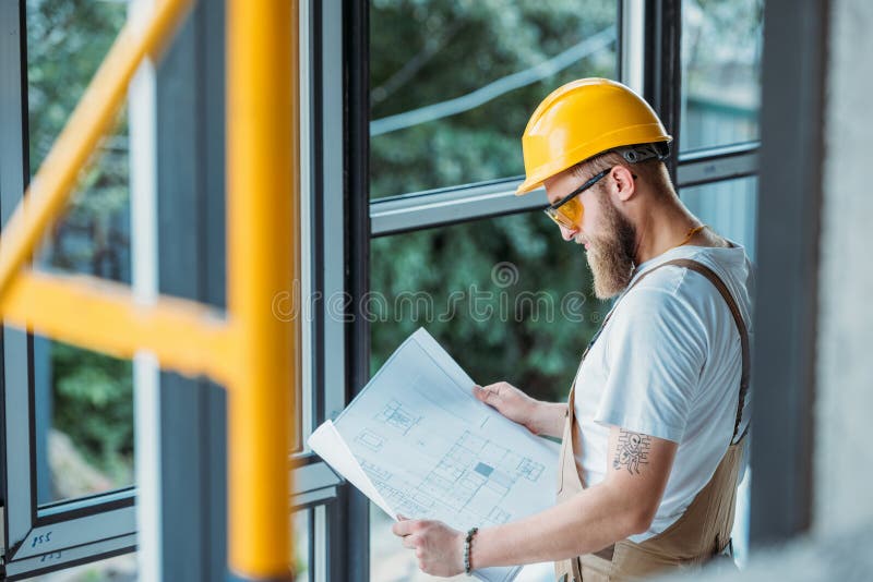 Side View of Builder in Hardhat and Protective Googles Looking at ...