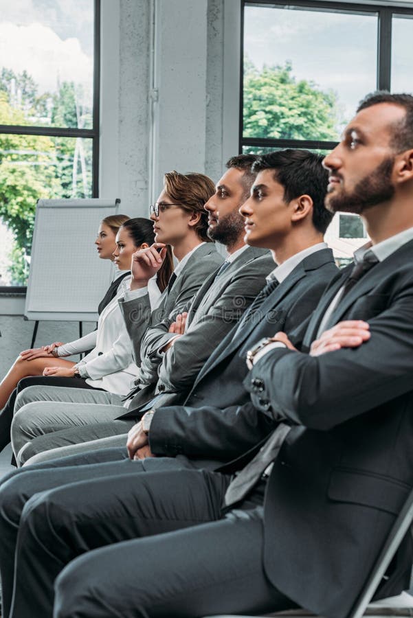 Side View of Businesspeople Sitting on Chairs during Training Stock ...