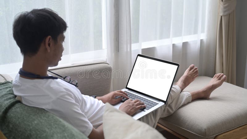 Casual Asian Man Resting on Couch at Home and Using Computer Laptop ...