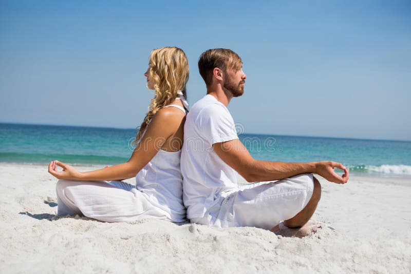 Side View of Couple Meditating at Beach Stock Photo - Image of back ...