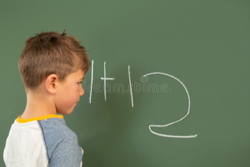 Schoolboy Doing Math on Green Chalkboard in a Classroom Stock Image ...