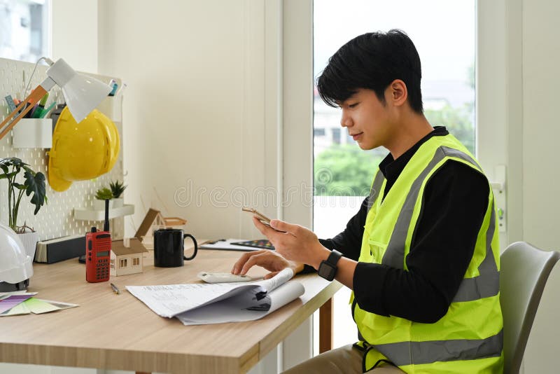 Side View of Engineer Using Smart Phone, Examining Construction Plans ...