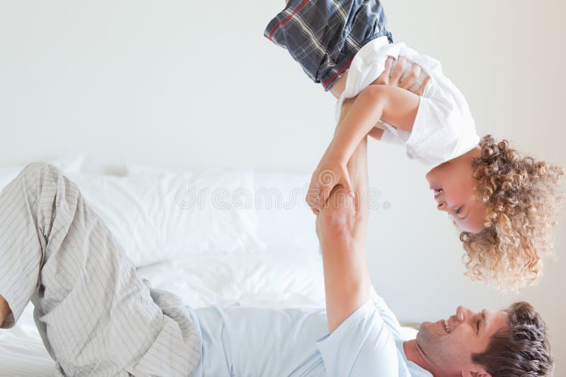 Side View of Father Lifting Child on Bed Stock Image - Image of ...