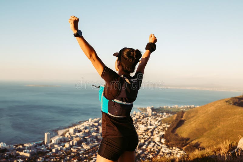 Side View of Female Runner with Arms Outstretched on Mountain Peak at ...