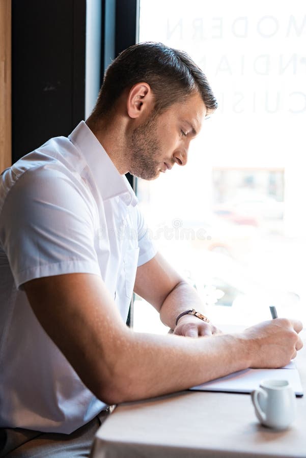 View of Focused Handsome Man Writing in Textbook in Cafe Stock Photo ...
