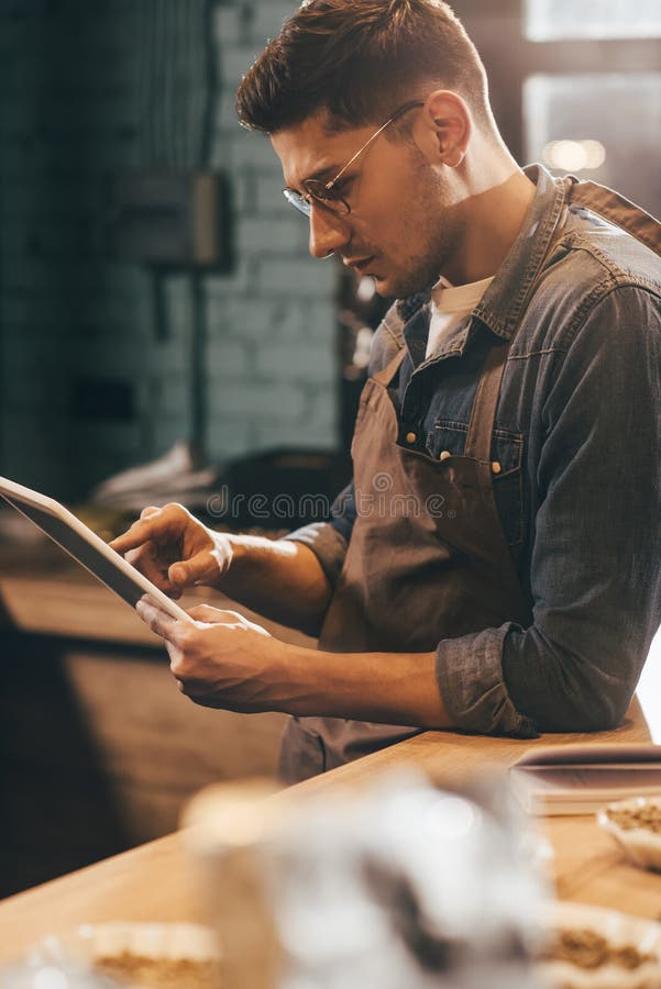 Side View of Focused Worker in Apron Using Tablet Stock Photo - Image ...