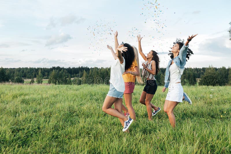 Side View of Four Female Friends Running on a Field and Throwing ...