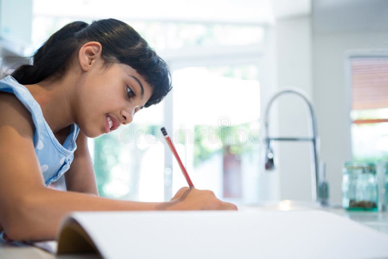 Side View of Girl Writing in Book Against Window Stock Photo - Image of ...