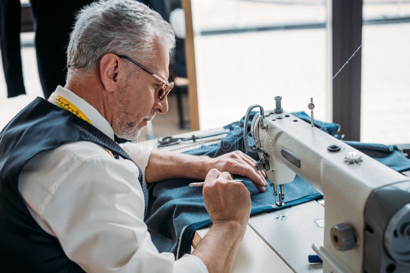 Side View of Grey Hair Tailor Sewing Cloth with Sewing Machine Stock ...