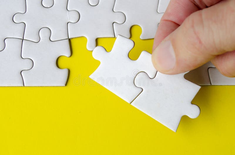 Side View of Hand Holding Jigsaw Puzzle Pieces on a Bright Yellow ...