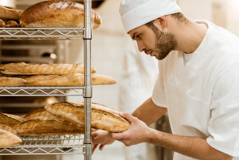 Side View of Handsome Baker Putting Fresh Bread on Shelf Stock Photo ...