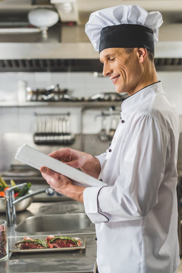 Side View of Handsome Chef Reading Recipe Book Stock Photo - Image of ...