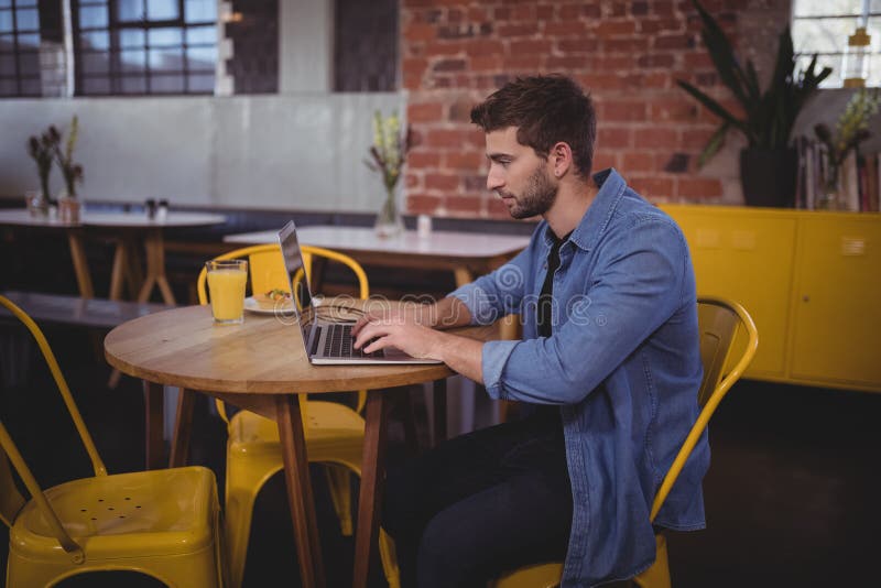 Side View of Handsome Man Typing on Laptop while Sitting at Table Stock ...