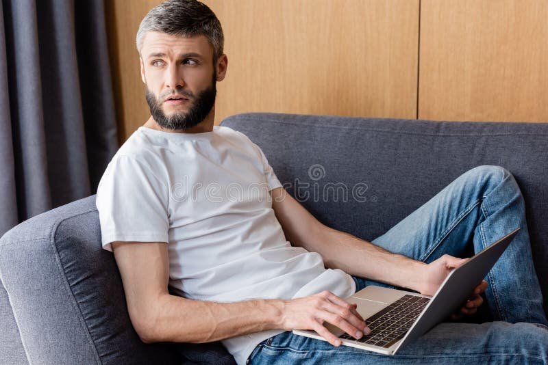 Side View of Handsome Teleworker Looking Away and Holding Laptop on ...