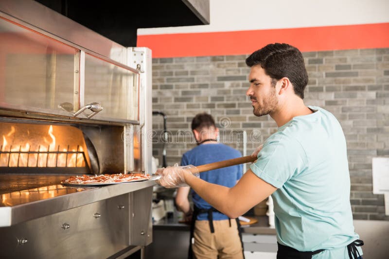 Chef Cooking Pizza And Putting It In The Oven To Bake Stock Photo ...