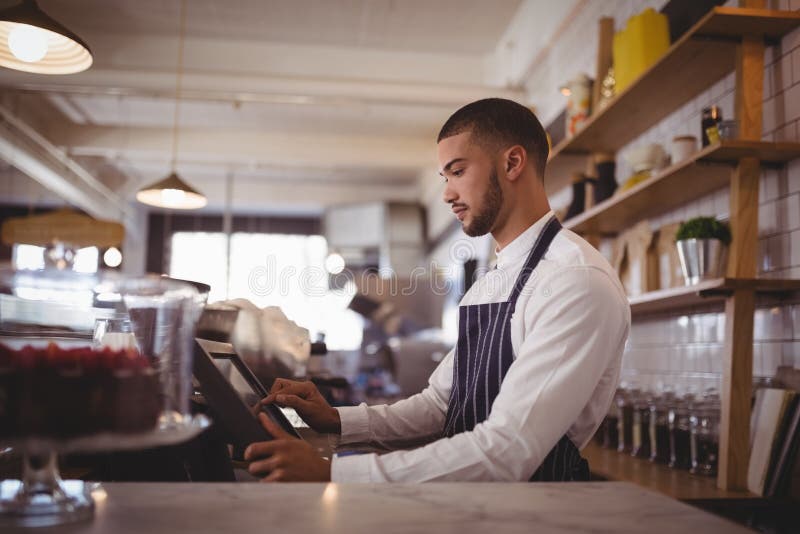 Side View of Handsome Young Waiter Using Computer at Counter Stock ...