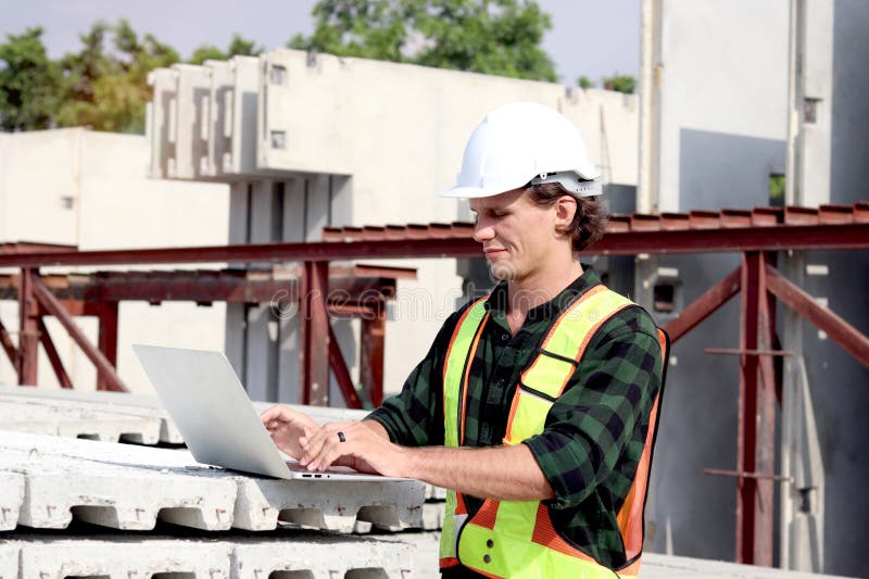 Side View of Happy Worker Engineer with Safety Vest and Helmet Typing ...