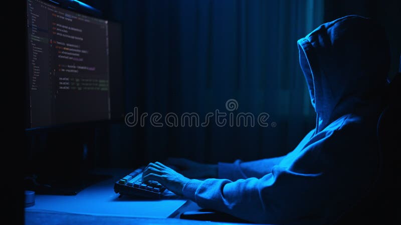 Side View Of Hooded Hacker Male Getting Access To Computer System Hacking Into Database